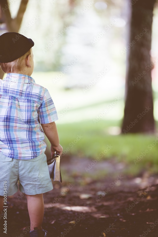 Vertical shot from a child from behind while holding the bible and a ...