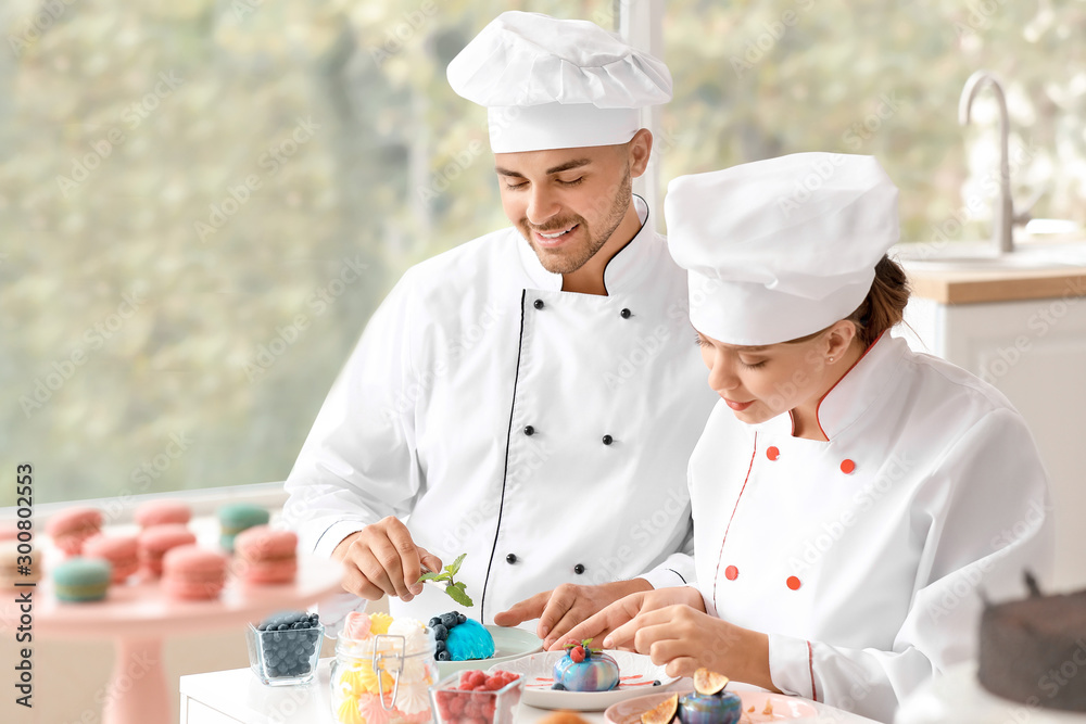 Young confectioners decorating tasty dessert in kitchen Stock Photo ...