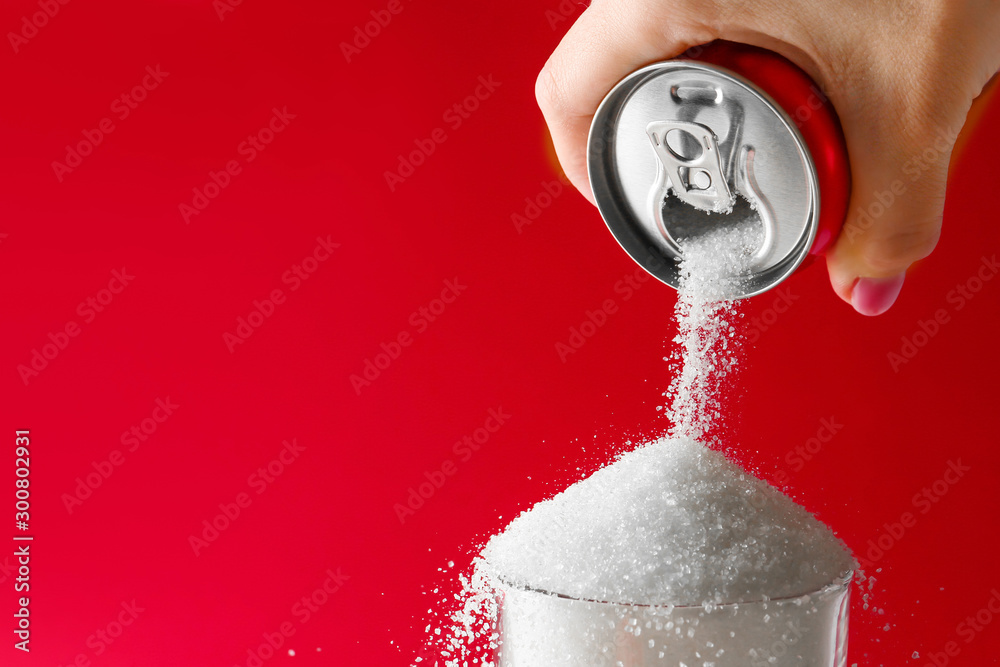 Pouring of sugar from can into glass on color background Stock Photo ...