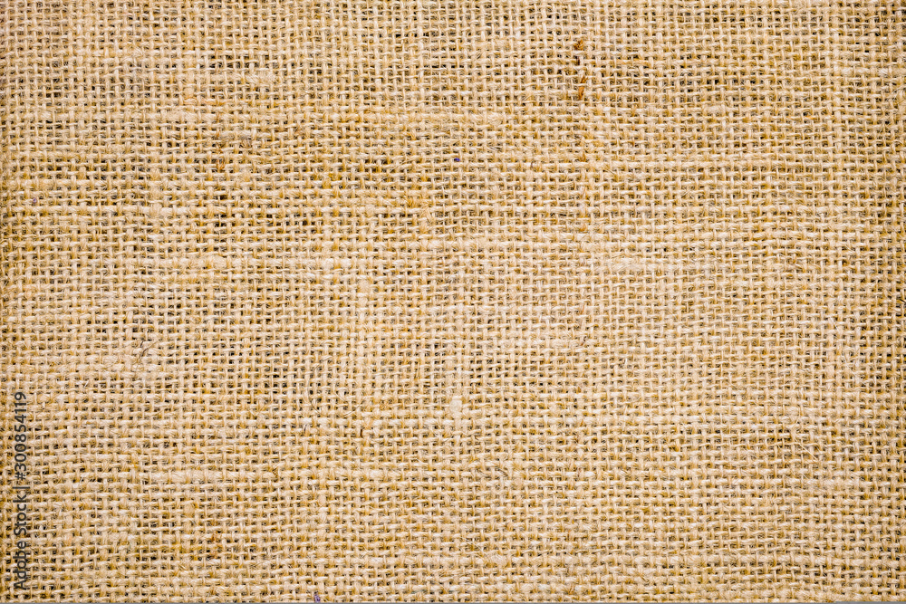 Rough hessian background with flecks of varying colors of beige and ...