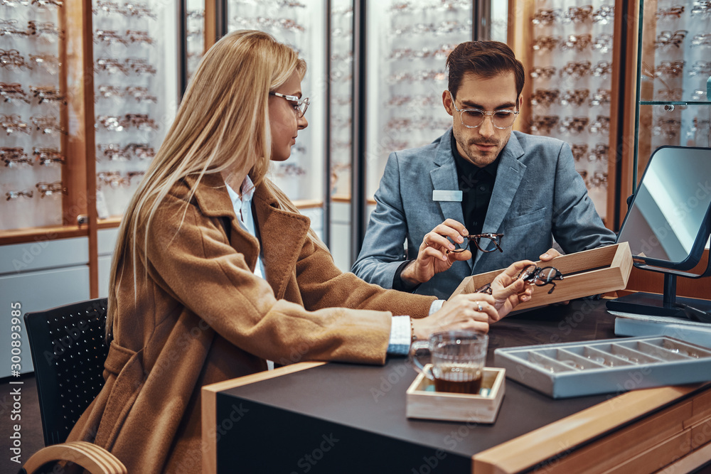 Professional salesperson helps a woman to choose reading glasses in an ...