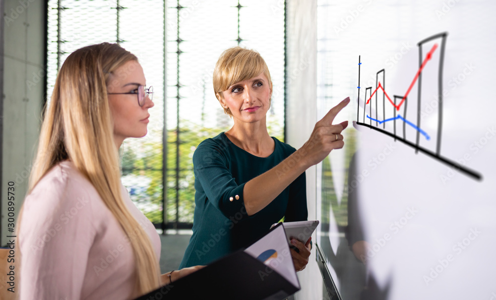 Two business woman talking about chart gives presentation at conference ...