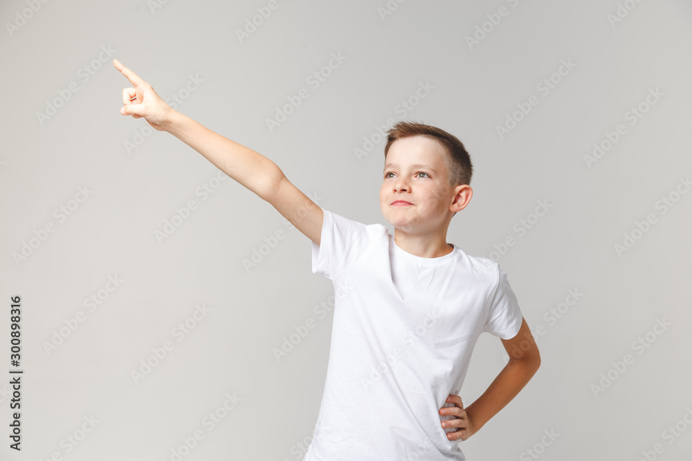 Handsome young boy stands in the pose of a hero, raising his hand up ...