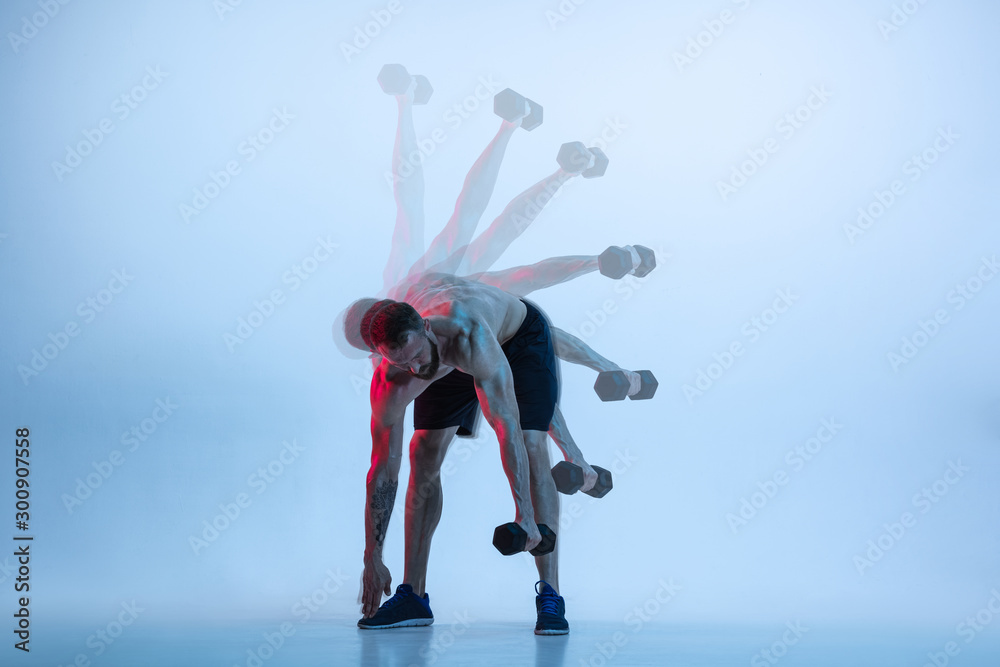 Flying. Young caucasian bodybuilder training over studio background in ...
