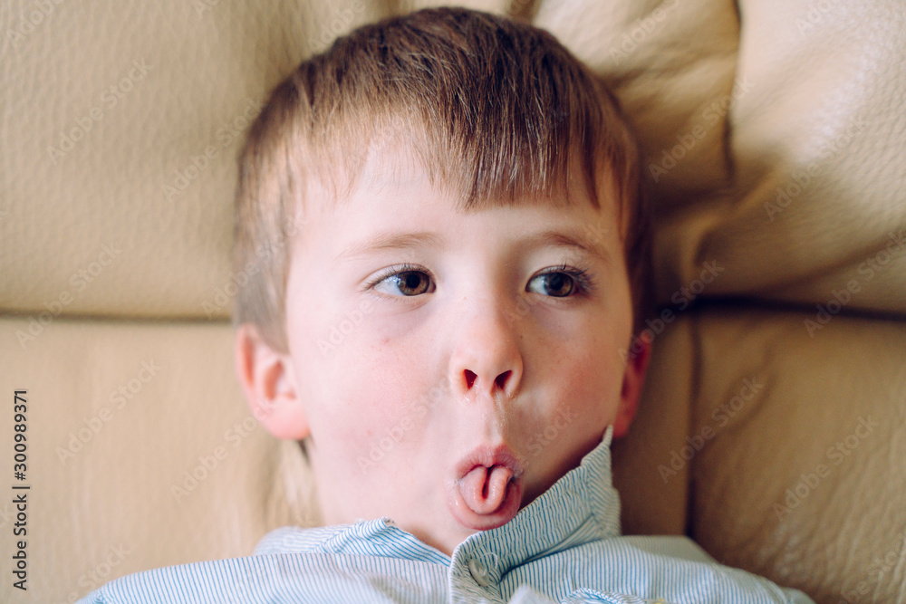 Portrait of a little naughty boy playing with slippery tongue with ...
