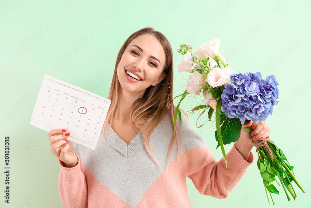 Beautiful young woman with calendar and flowers on light background ...