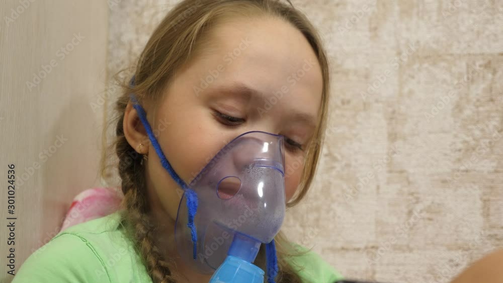 child with a tablet is sick and breathes through an inhaler. close-up ...