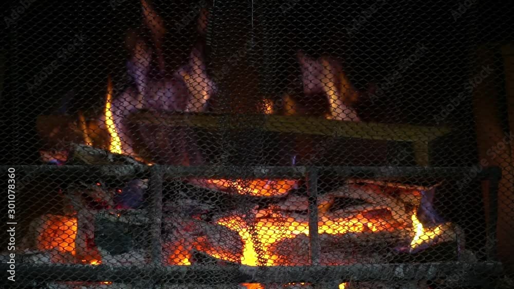 Slow burning logs In a vintage brick fireplace with screen in front of ...