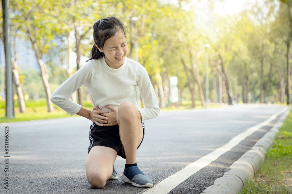 Sick asian child girl holding her hands on belly having stomach painful ...