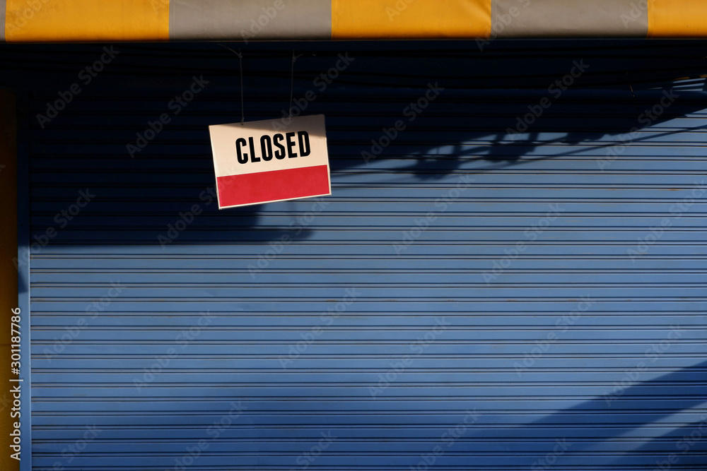Sunlight and shadow on surface of hanging closed sign board in front of ...