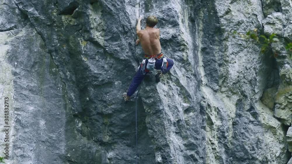 back view strong muscular man rock climber climbing on sport route ...