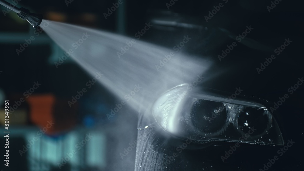 Car headlight wash. Washing modern vehicle body by high pressure jet ...