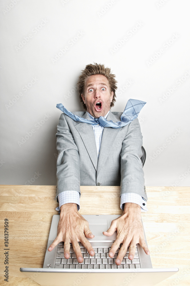 Shocked businessman blown away at his desk by what he finds on his ...