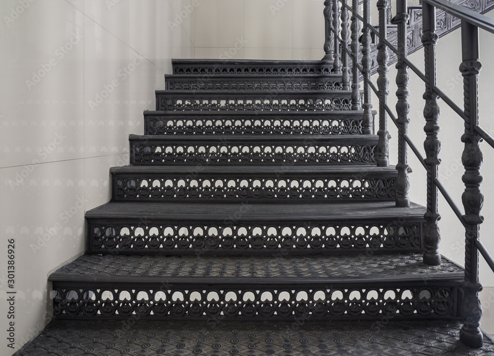 Antique metal staircase with black richly decorated wrought-iron steps ...