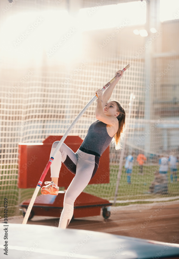 Pole vaulting indoors - young sportive woman with a ponytail leaning on ...