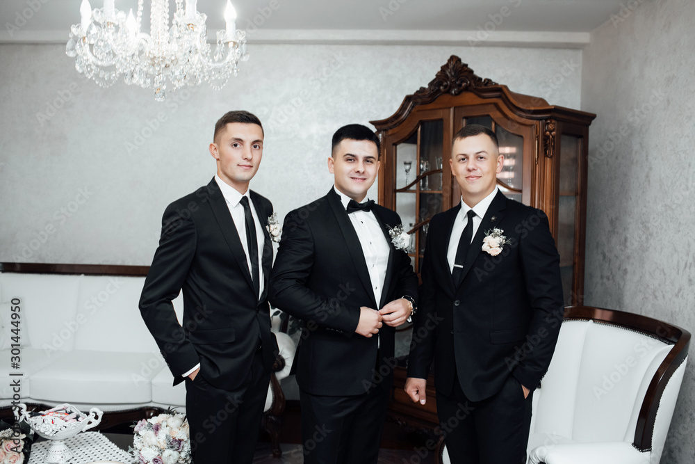 Stylish groom posing and having fun with groomsmen while getting ready ...