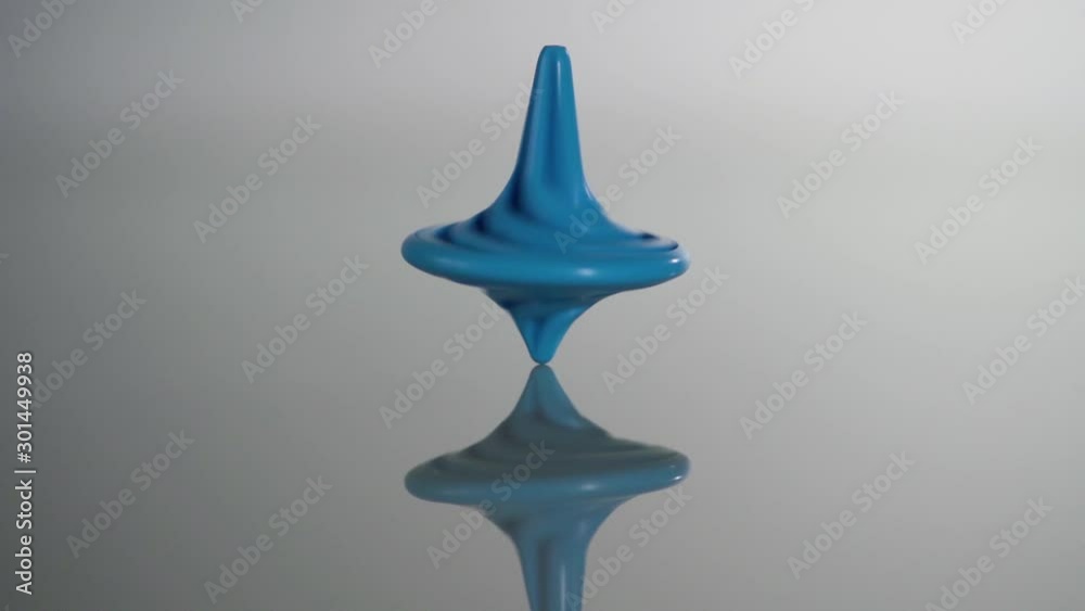Blue spinning top spinning. Whirligig in action is reflected on mirror ...