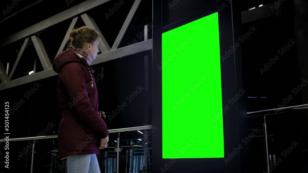 Woman looking at vertical blank interactive green display kiosk at ...
