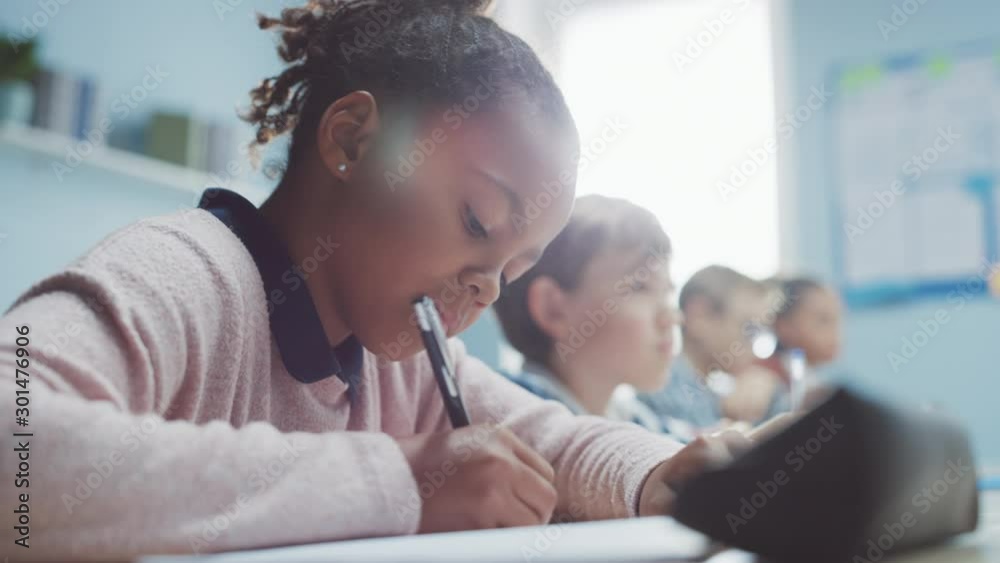 In Elementary School Classroom Black Girl Writes in Exercise Notebook ...