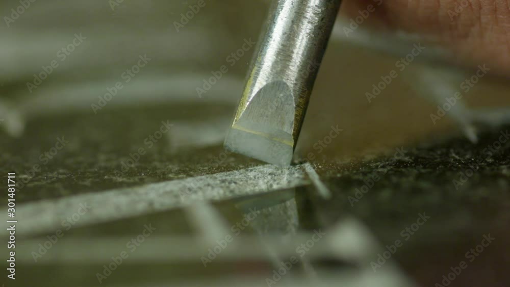 Closeup of process of professional manual engraving letters on surface ...