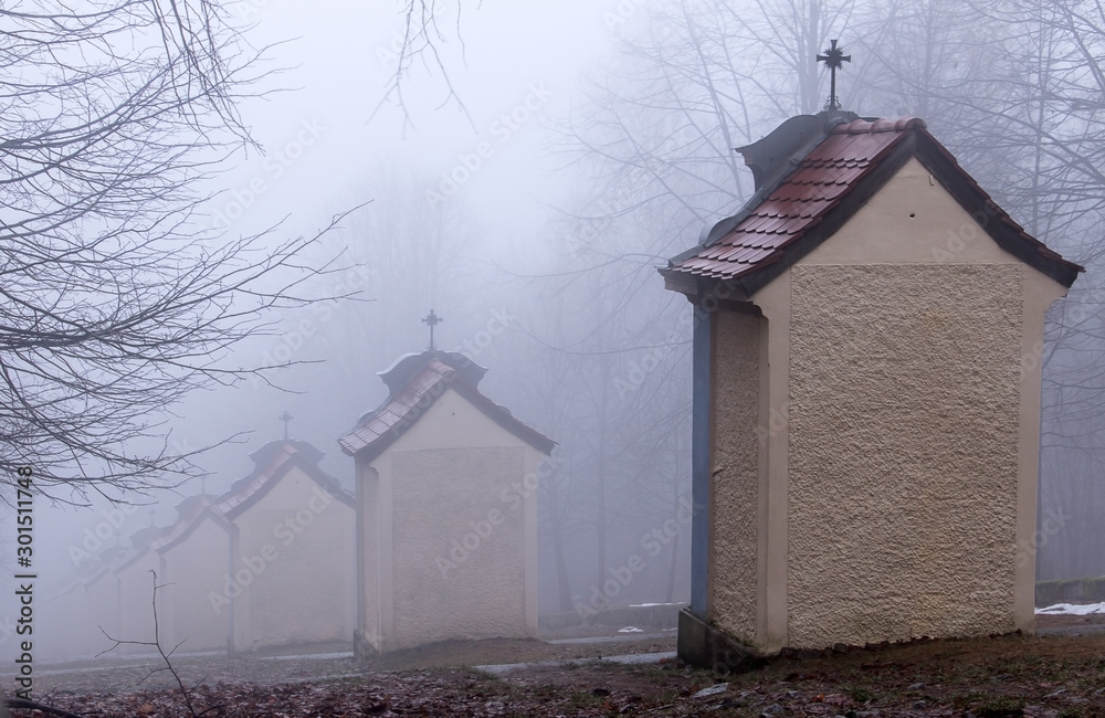 Stations of the Cross on a hill in winter fog. Clouds before sunset ...