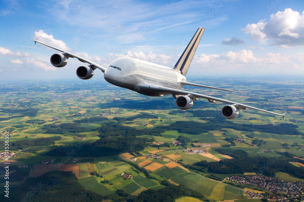 White aircraft in flight. The passenger plane flies high over the green ...