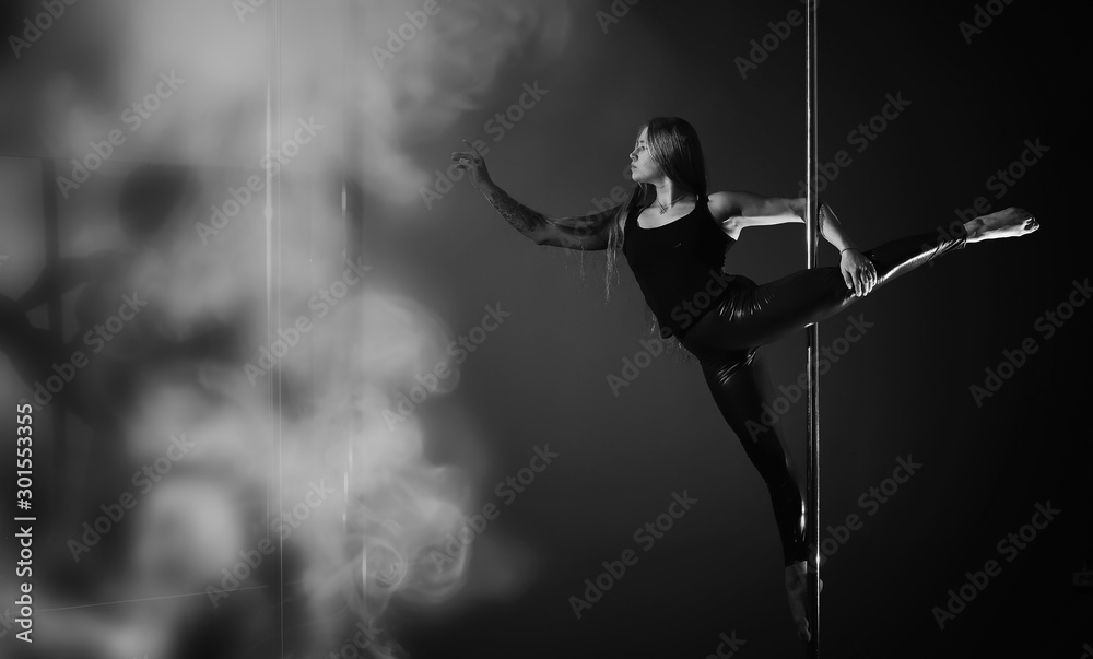 The dancer on the pylon in the studio. Girl doing exercises on a sports ...