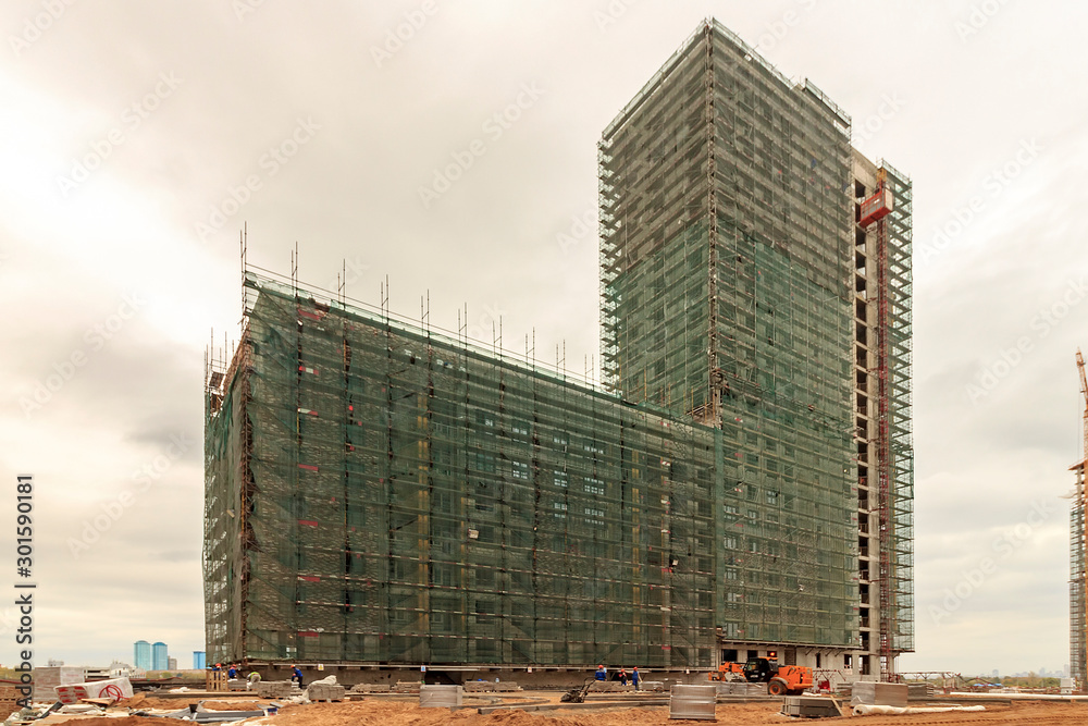 Tall building under construction with scaffolds. Construction site ...
