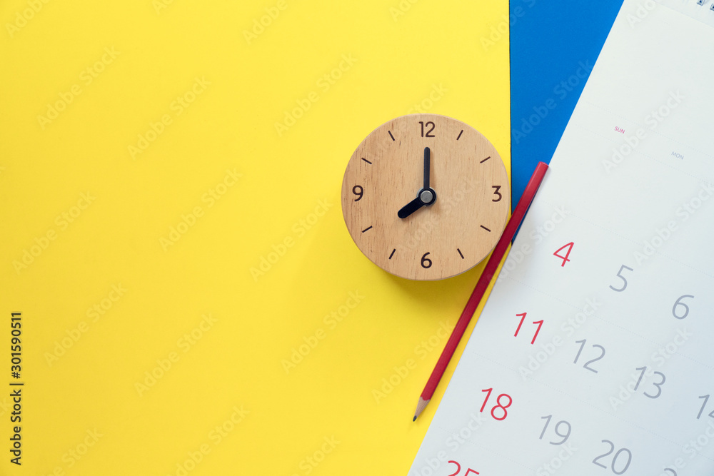 close up of calendar, clock and pencil on the yellow and blue table ...