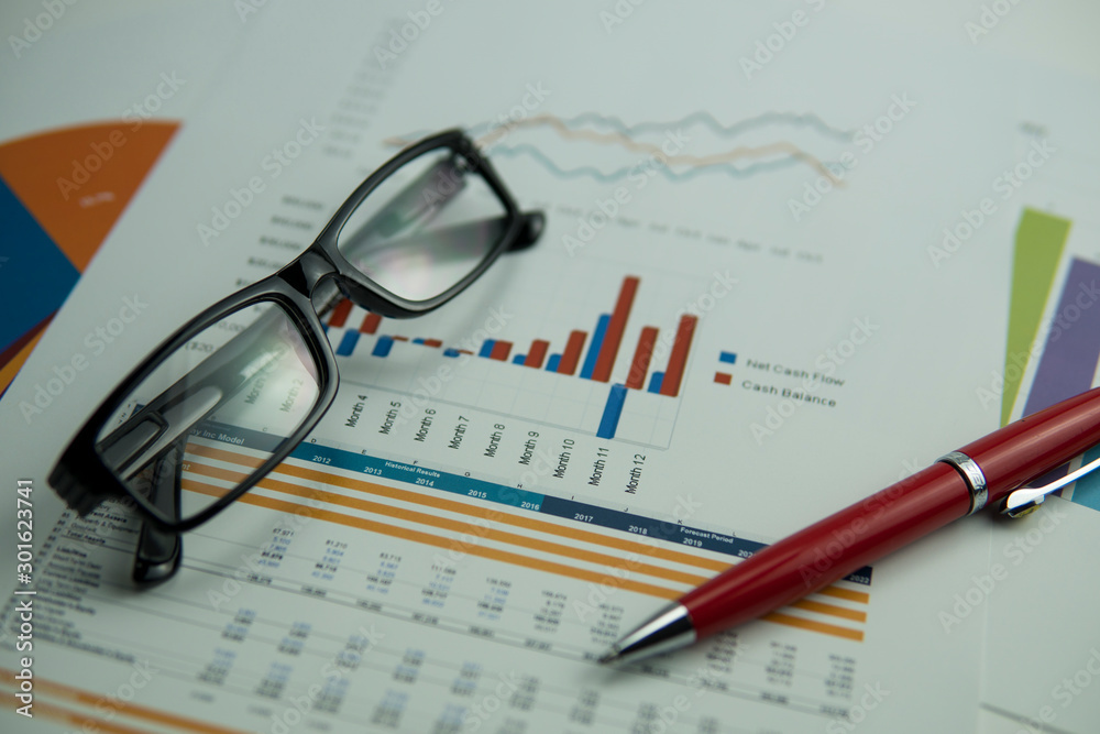 Selective focus of chart graph document with eye glasses and pen on top ...
