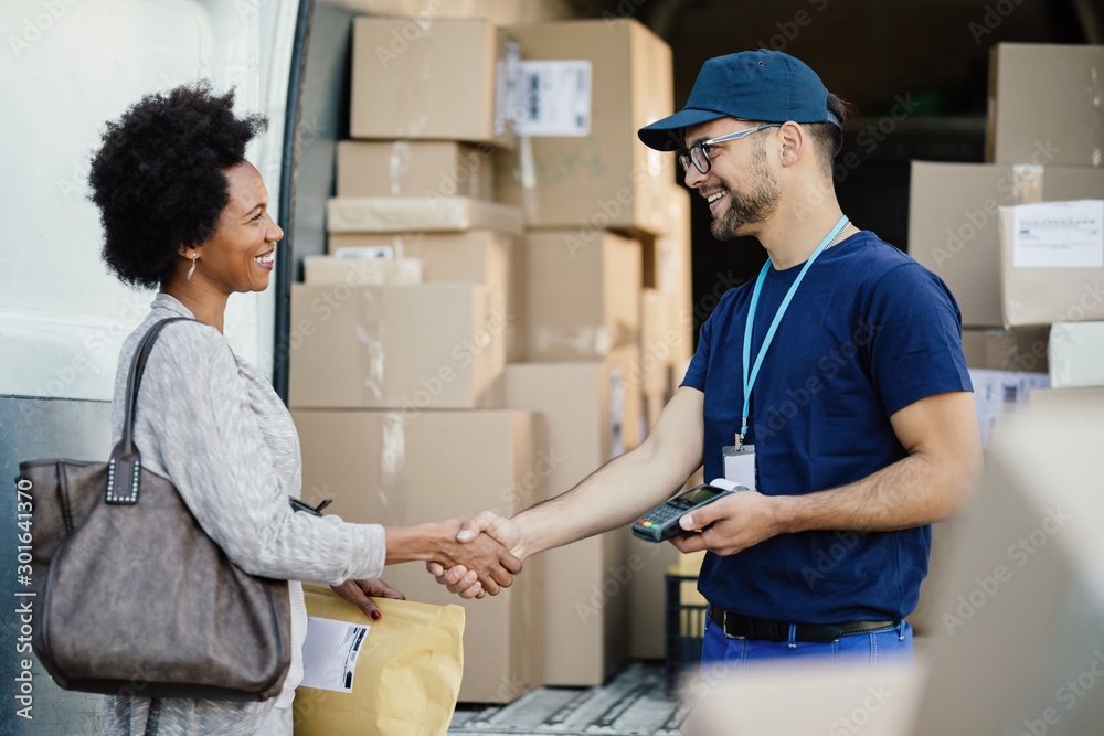 African American woman shaking hands with delivery man while receiving ...