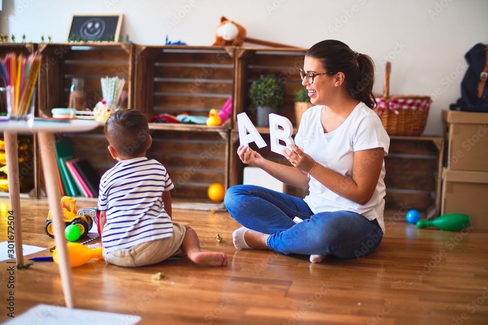 Beautiful teacher teaching alphabet to student toddler boy at ...