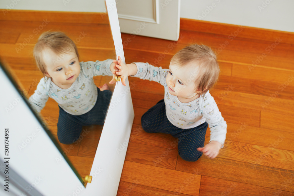 Baby girl playing with her reflection in mirror Stock Photo | Adobe Stock