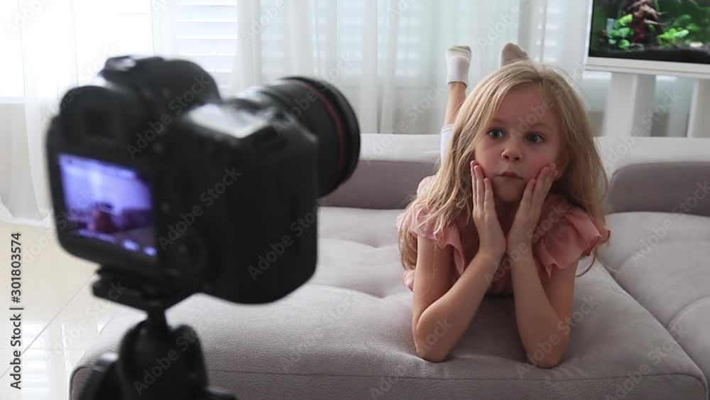 Funny little girl smiling looking at camera at home, cute kid talking ...