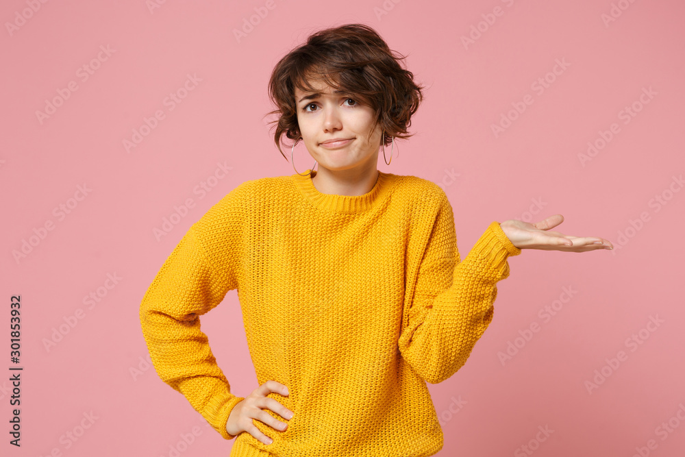 Confused young brunette woman girl in yellow sweater posing isolated on ...