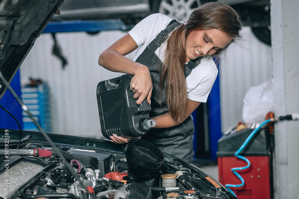 Beautiful Mechanic girl in a black jumpsuit and a white T-shirt changes ...