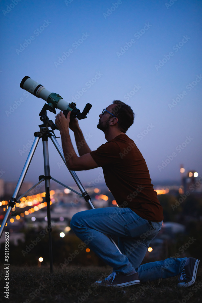 Astronomer with a telescope watching at the stars and Moon with blurred ...