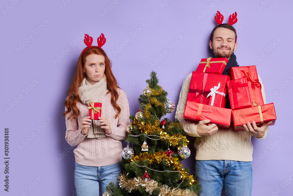 Delighted bright man holding various gifts, satisfied with surprise ...