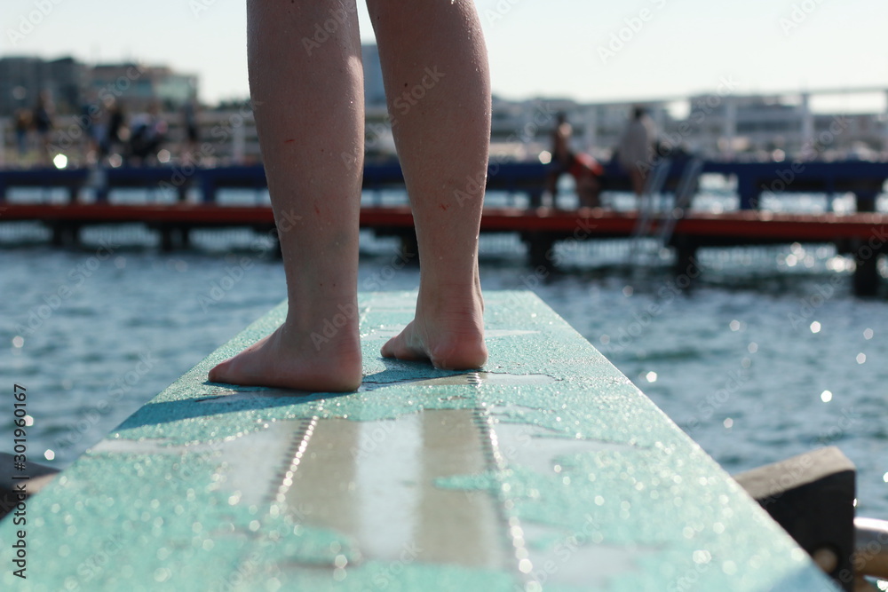 feet of a diver ready to dive off a blue diving board pocking out over ...