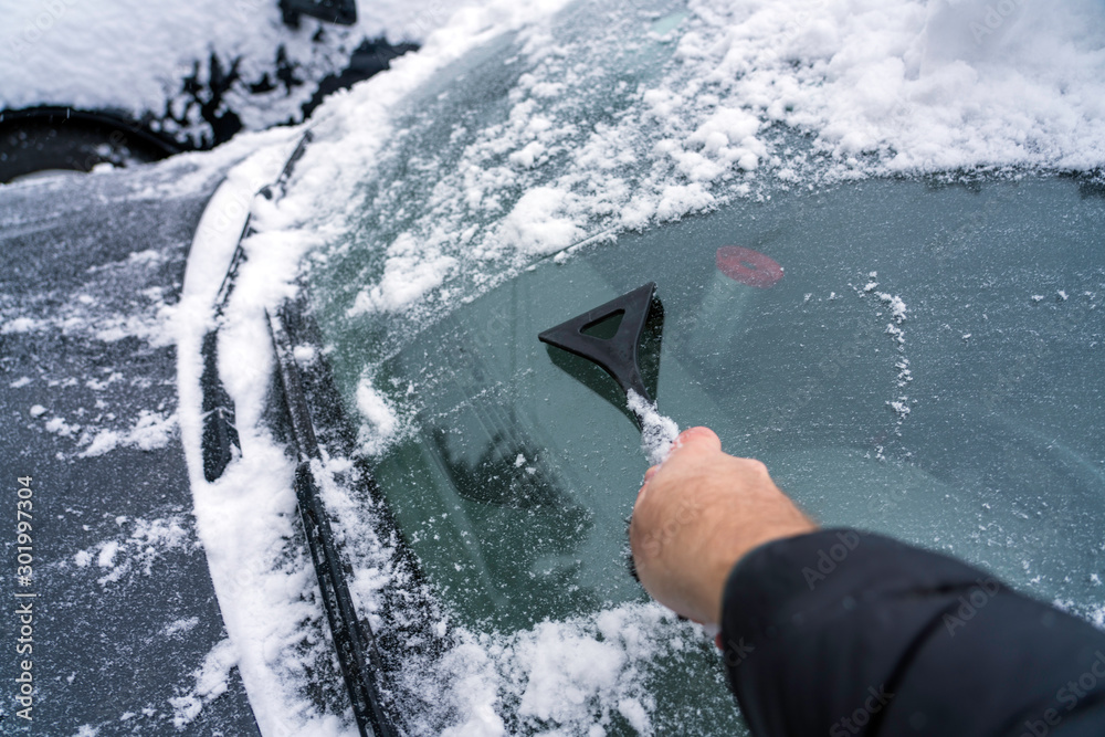 Hand are holding scraper and scraping car window clean of ice and snow ...