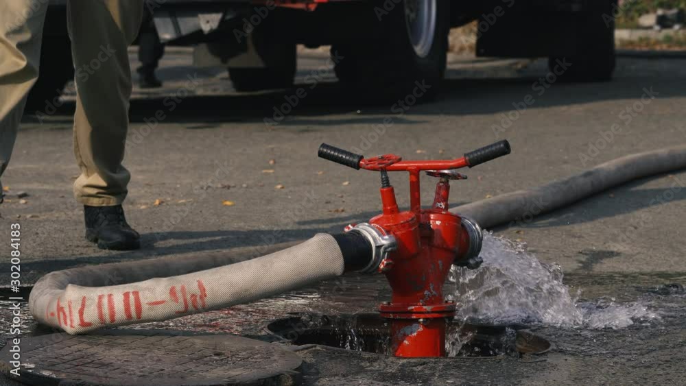Firefighter sets up a hydrant. A stream of water from a fire hydrant ...