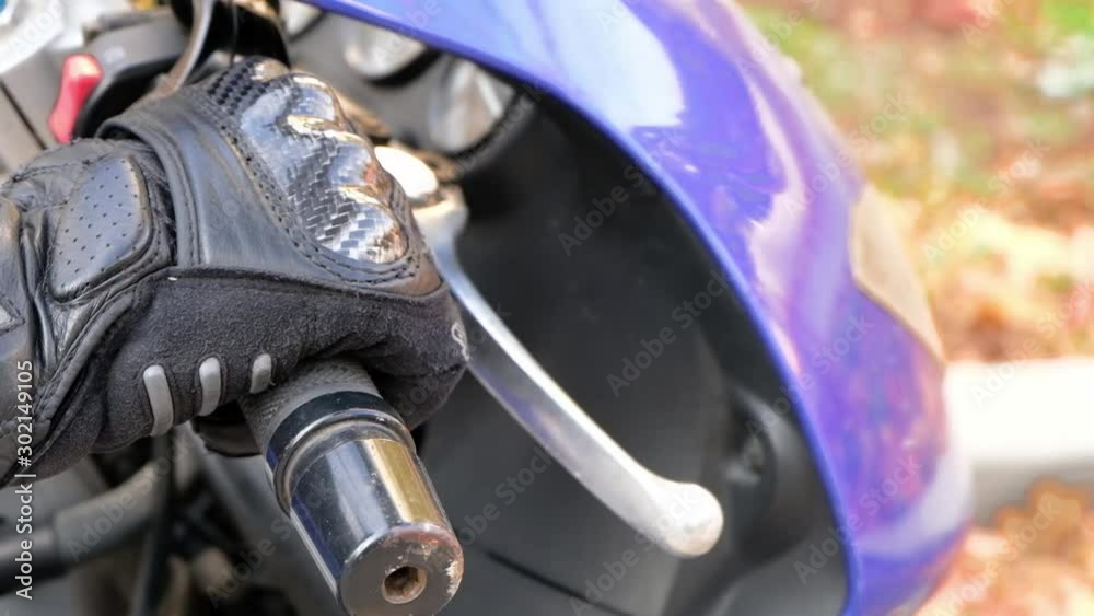 Close up shot of man in gloves holding twist grip throttle and revving ...