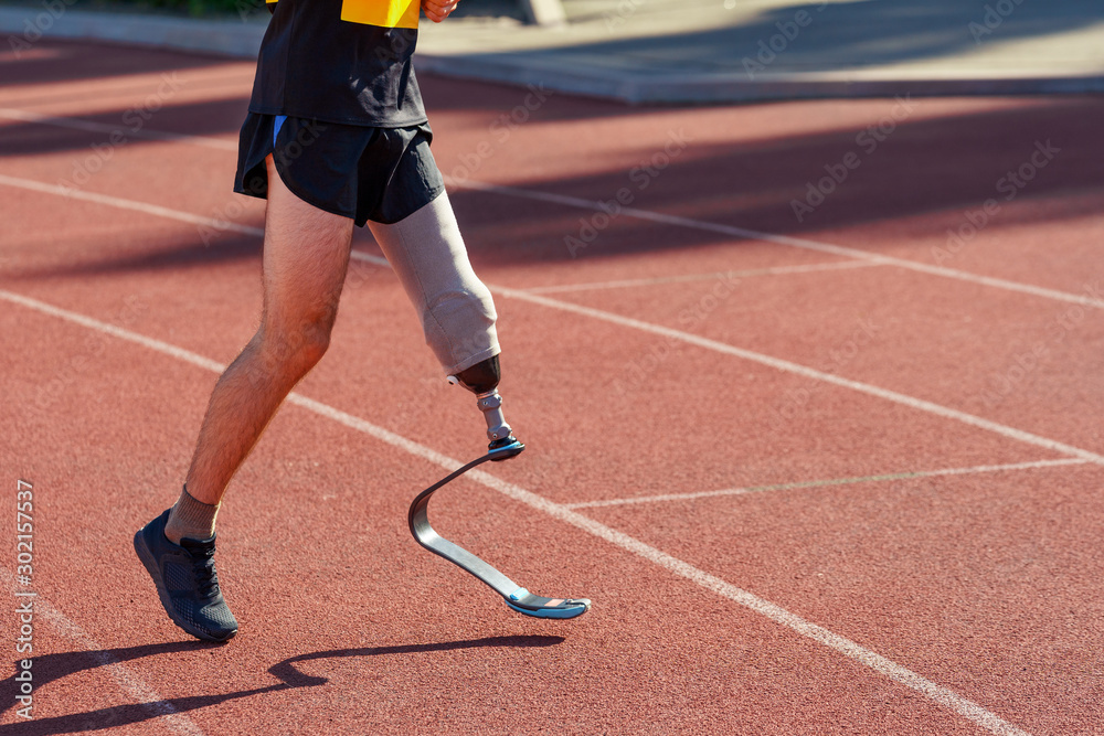 Low-section portrait of amputee sportsman. Athlete running on a track ...