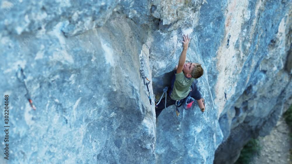 top view of little scared and tensed boy rock climber, climbing on a ...