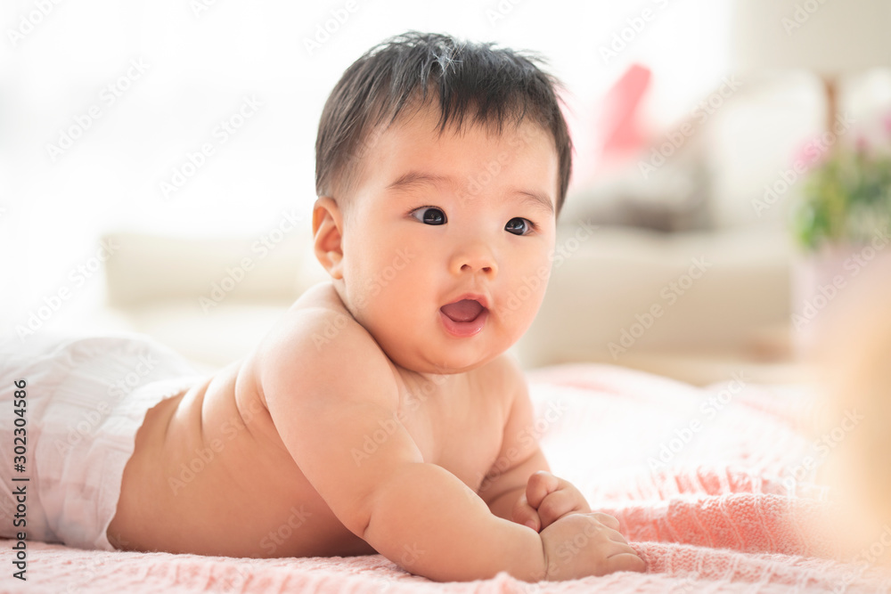 Little Chinese baby lying on front in bed Stock Photo | Adobe Stock