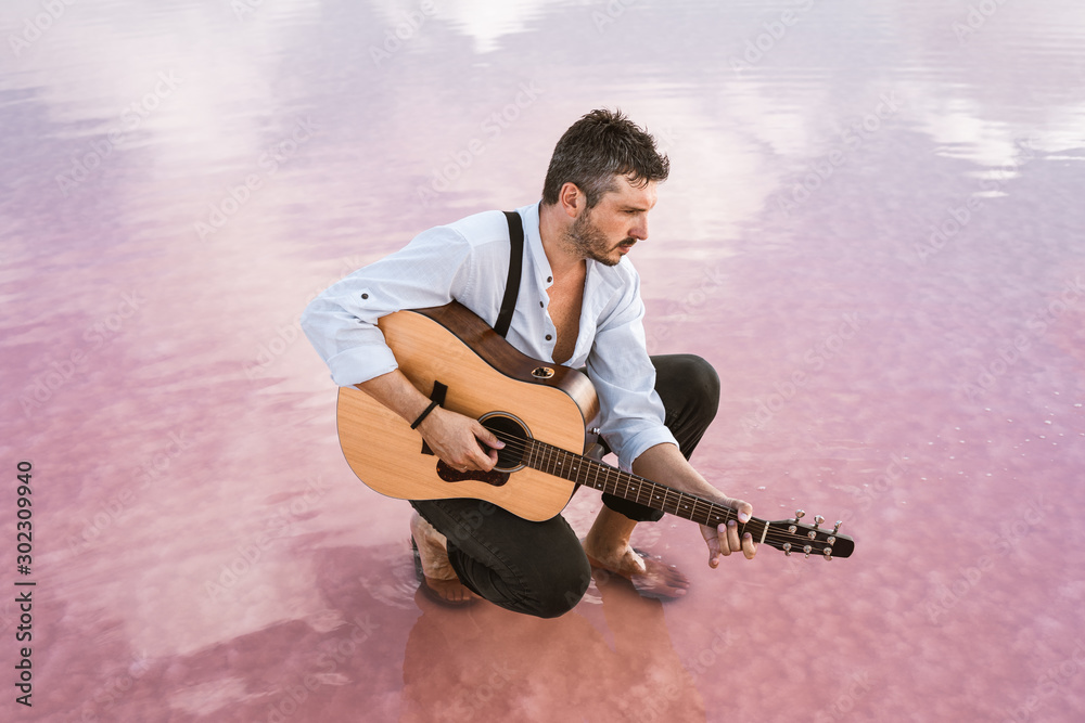 Wistful man in white shirt and suspenders carrying acoustic guitar and ...