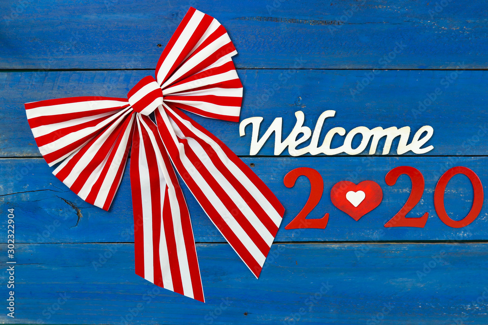 Welcome year 2020 in bold red and large bow on antique rust blue wood ...