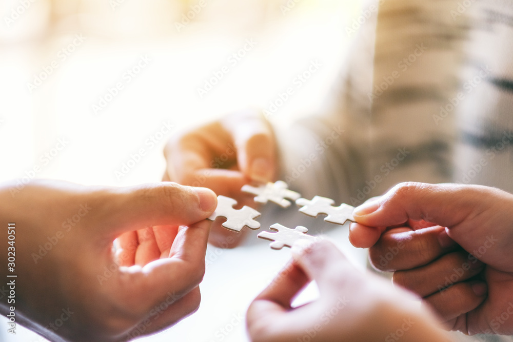 Closeup image of many people holding and putting a piece of white ...