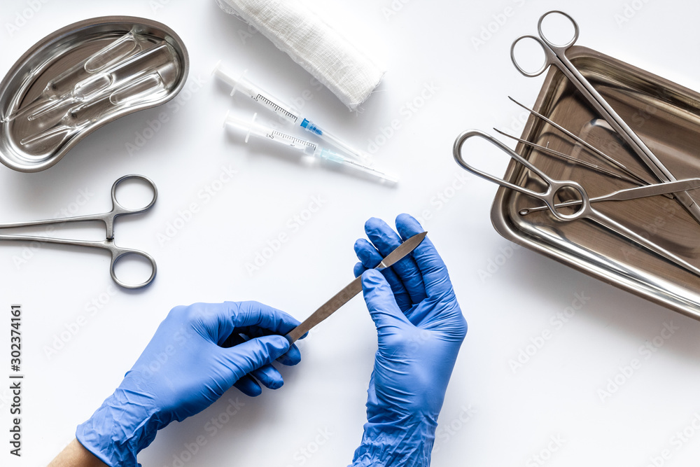 Preparing for plastic surgery. Doctor's hands takes scalpel on white ...