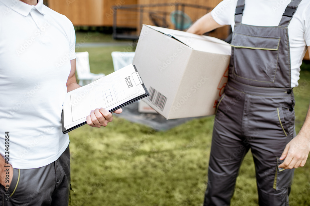 Delivery men with checklist and cardboard boxes outdoors, close-up view ...